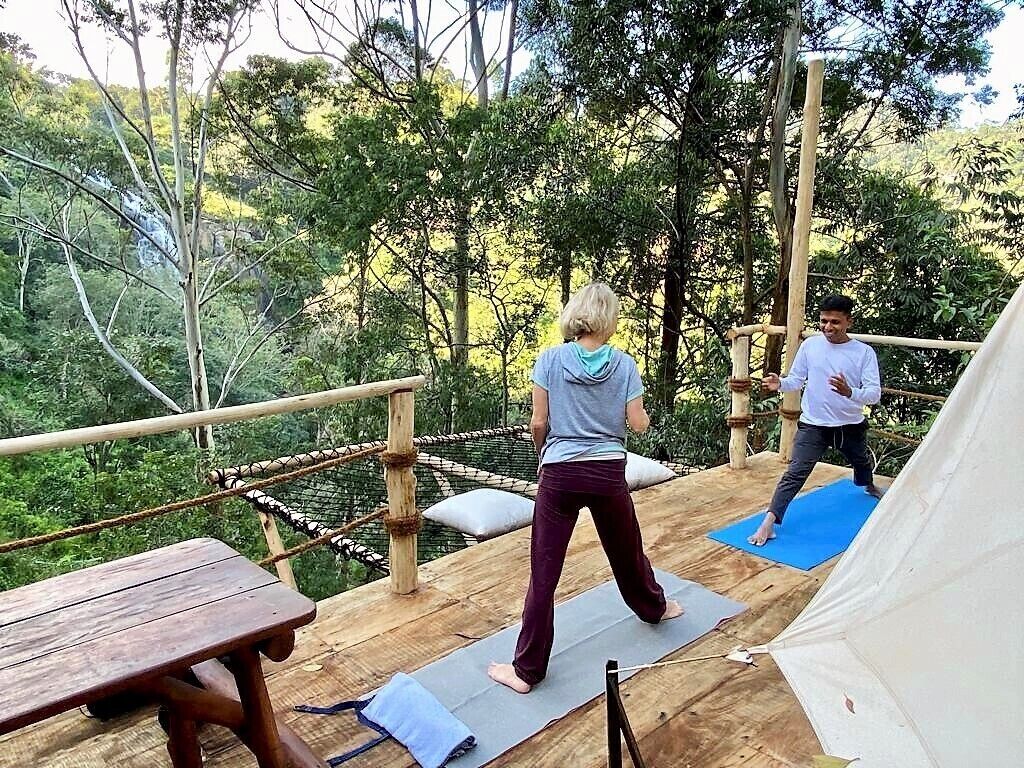 Um deck de madeira com uma ponte de corda, uma mesa de madeira e uma tenda.