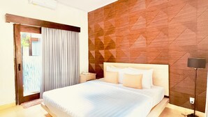 Quarto com cama grande, mesa de cabeceira, ar condicionado fixado na parede e papel de parede estampado.