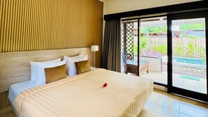 Quarto de hotel com uma cama grande, cabeceira de madeira, luz de teto e vista para o exterior através de uma porta de vidro.