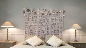 Quarto com cama, duas mesas de cabeceira, duas lumin árias e uma cabeceira decorativa.