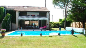 Um edifício com piscina, área de estar ao ar livre e um pátio coberto.