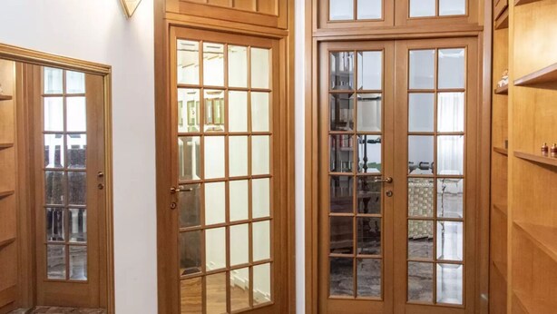 Um corredor com portas de madeira e vista para um quarto com lareira.