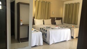 Quarto de hotel com duas camas, um guarda-roupa de madeira e cortinas verdes.