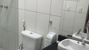 Casa de banho com sanita, lavatório e lixeira.
