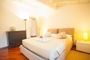 Um quarto com cama, mesa de cabeceira, cômoda e abajur.