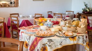 Mesa de jantar posta com diversos alimentos, incluindo doces, frutas e acompanhamentos.