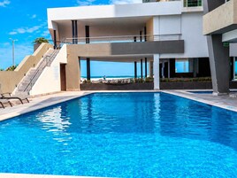 Um edifício moderno com piscina, escadas externas e vista clara do oceano.