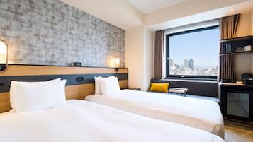 Quarto de hotel com duas camas, vista para a cidade, uma mesinha e uma televisão.