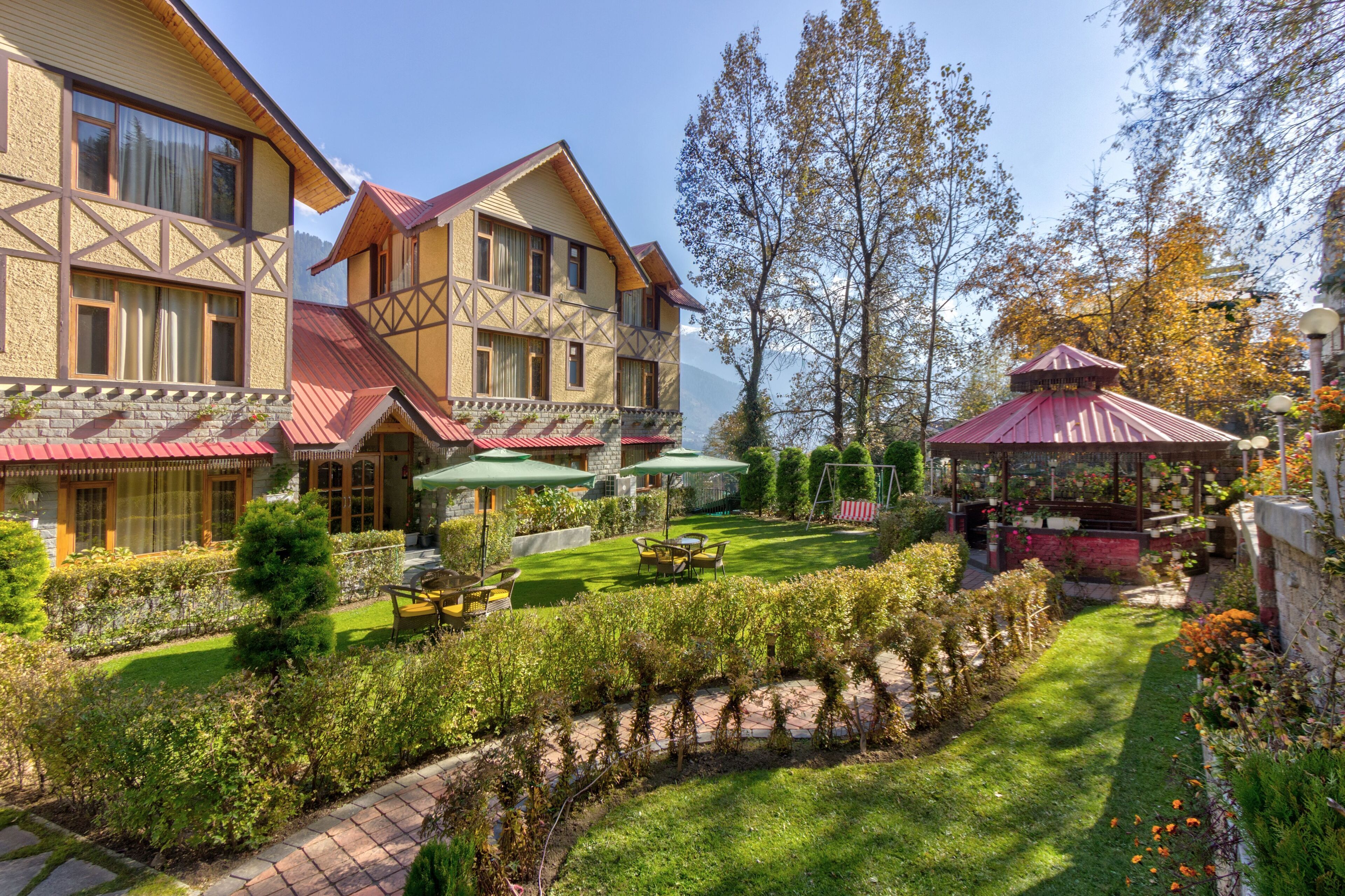 Um chalé de estilo tradicional com um jardim bem cuidado, área de estar externa e um gazebo.