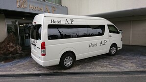 Uma carrinha branca estacionada em frente a um edifício com uma placa que diz 'Hotel A.P.'