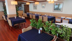 Restaurante com várias mesas cobertas por toalhas azuis, dispostas em fileiras.