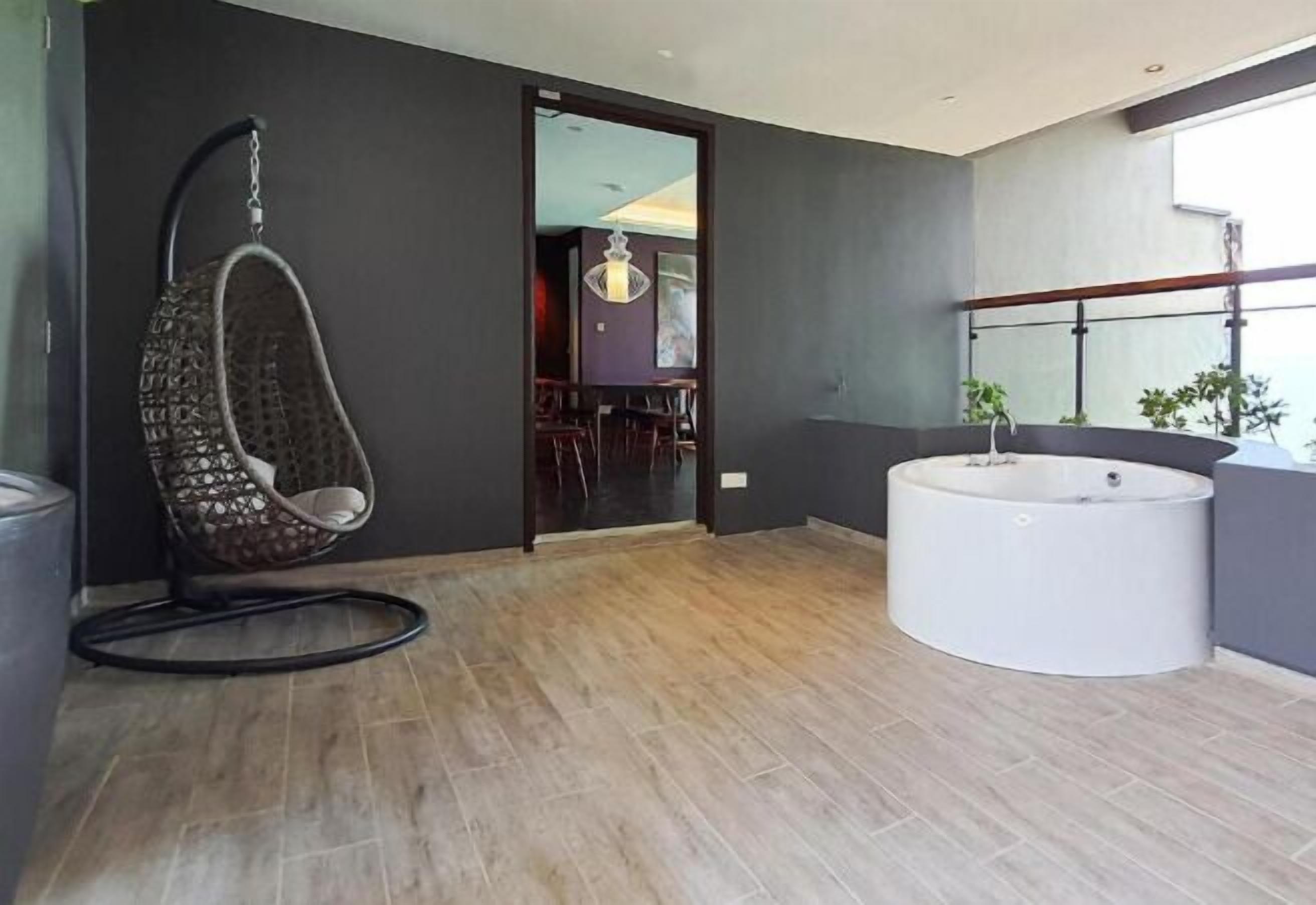 Casa de banho moderna com uma banheira grande, uma cadeira suspensa e vista para a sala de jantar.