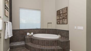 Um banheiro moderno com uma banheira de imersão, uma janela com persianas e um detalhe decorativo na parede.