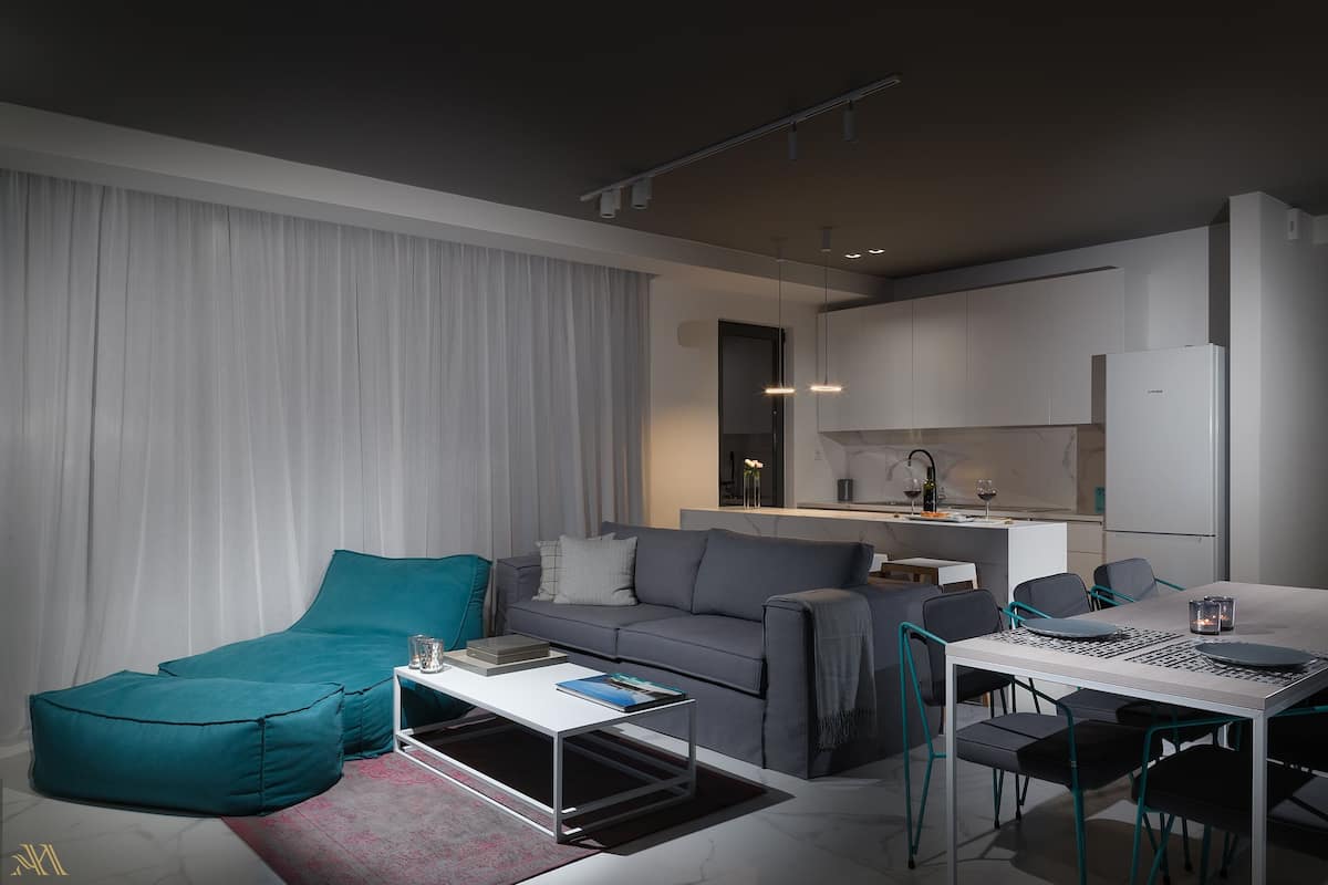 Uma sala de estar moderna com sofá, banquinho, mesa de centro e área de jantar.