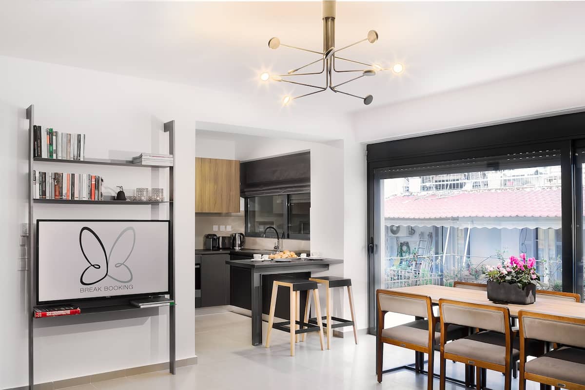 Cozinha moderna com área de refeições, estante de livros e um letreiro com a inscrição 'BREAK BOOKING'.