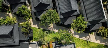 Vista aérea de um bairro residencial com várias casas, cada uma com telhados escuros e cercada por vegetação.