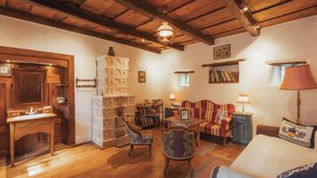 Um quarto aconchegante com piso de madeira, uma escrivaninha de madeira, um armário estampado, um sofá e uma cama com travesseiro decorativo.