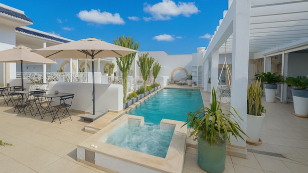 Uma área de piscina no terraço com hidromassagem, mobiliário de exterior e plantas em vasos.