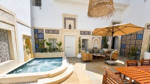 Piscina com hidromassagem, área de estar externa e pérgola.