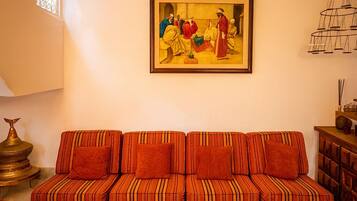 Uma sala de estar com sofá, um quadro, um abajur decorativo e uma mesinha.