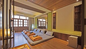 Quarto de hotel moderno com uma cama grande, área de estar e uma janela ampla.