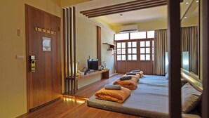 Quarto de hotel com uma cama grande, televisão, escrivaninha e janela com cortinas.