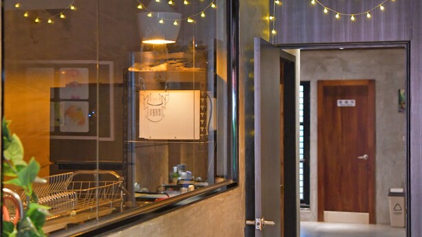 Um lobby de hotel moderno com balcão de recepção, porta de madeira e luzes de cordão.
