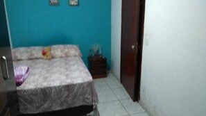 Um quarto com cama, cômoda e porta.