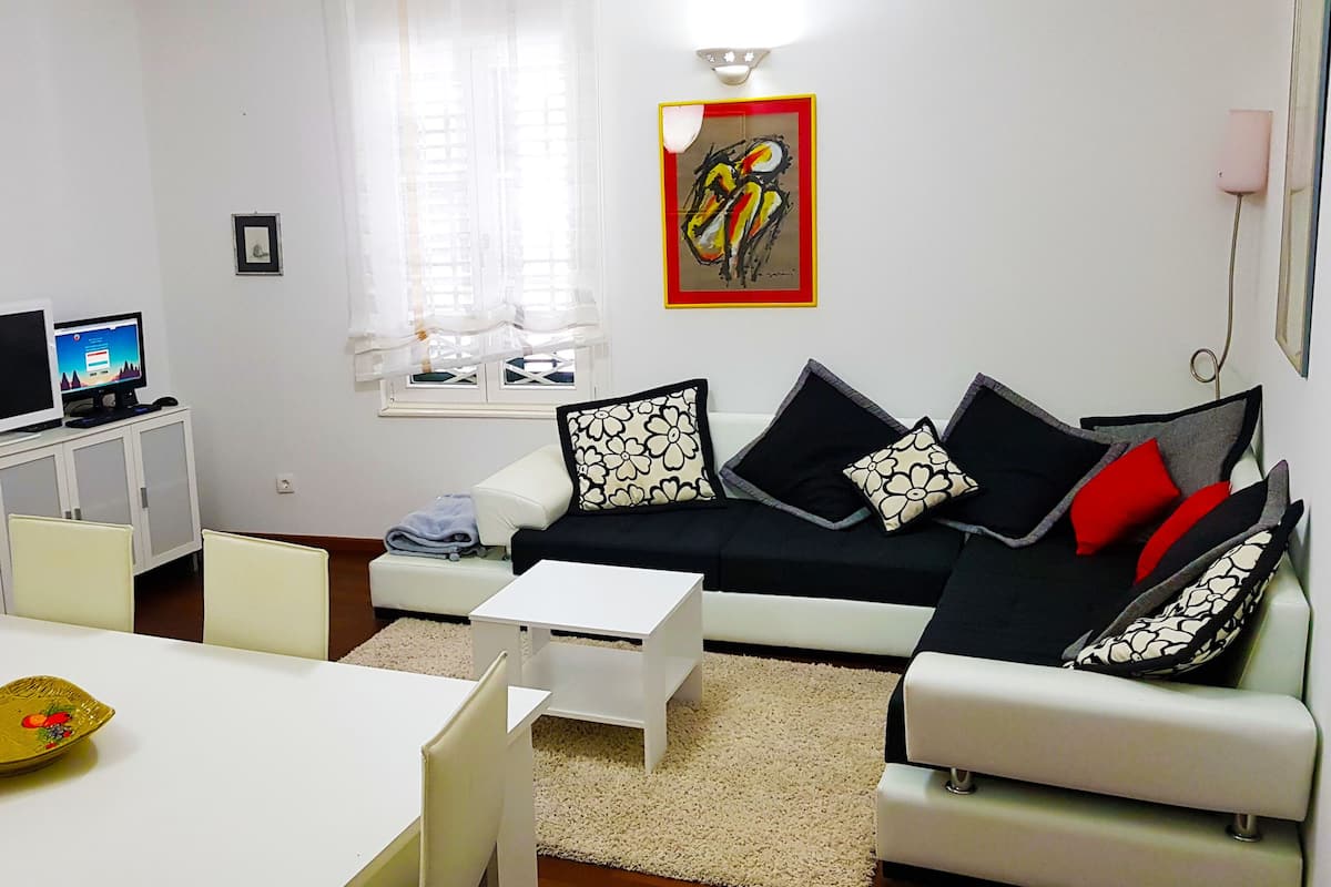 Uma sala de estar moderna com um sofá, uma TV, uma mesa pequena e uma tigela decorativa.