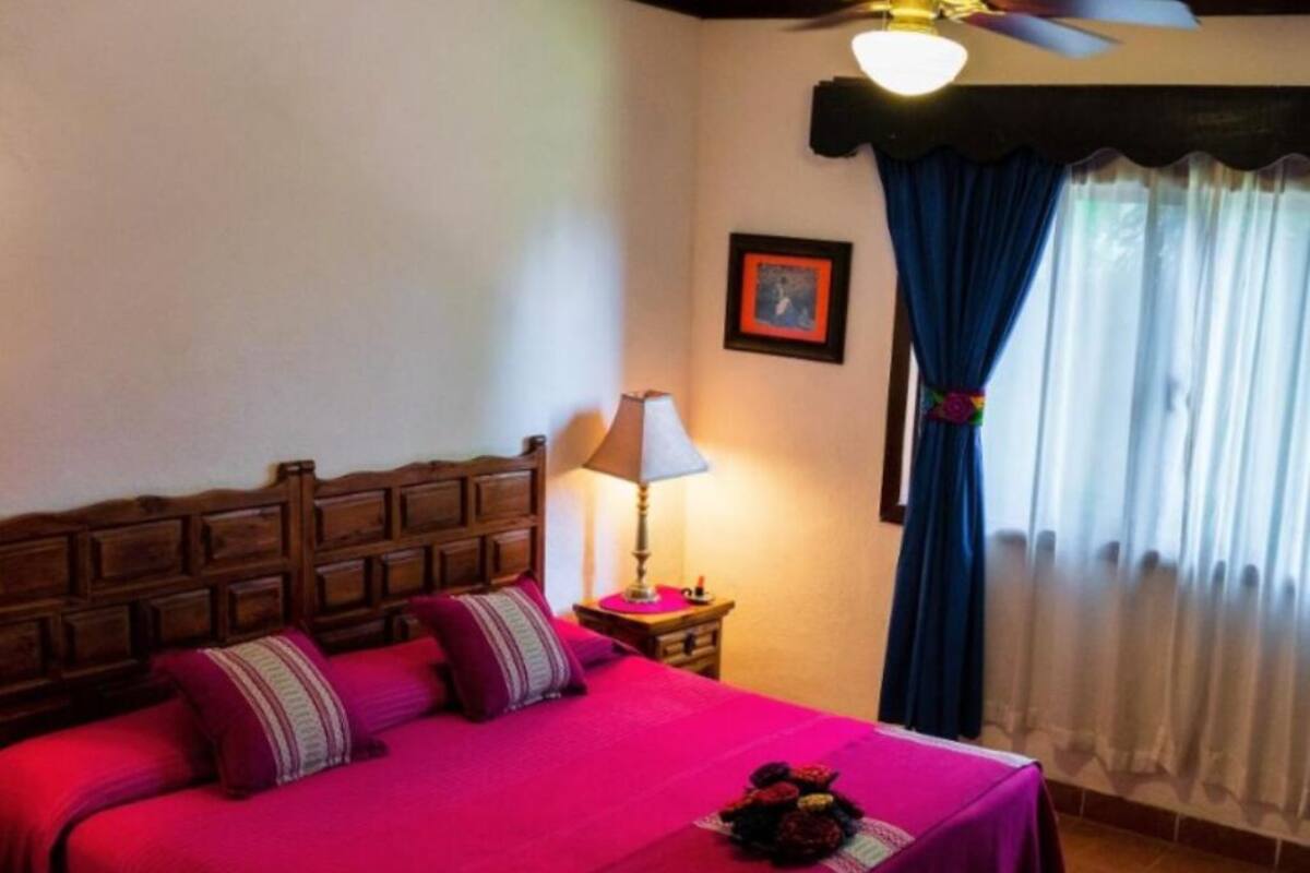 Uma cama com cabeceira de madeira, uma luminária de cabeceira e um quadro na parede.