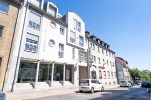 Um hotel com fachada moderna, grandes janelas e entrada visível com degraus.