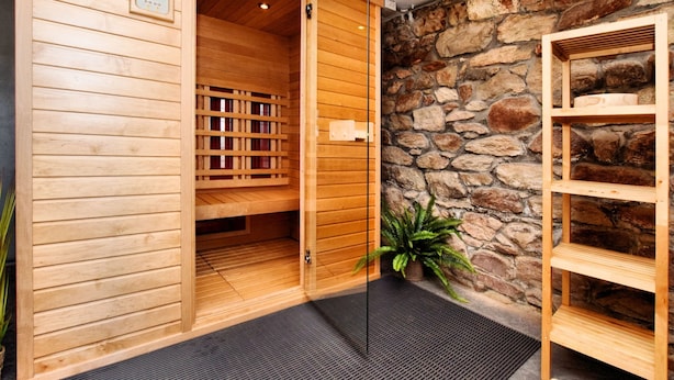 Uma sauna de madeira com parede de pedra e prateleira de madeira.