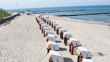 Uma praia com fileiras de cabanas de praia numeradas ao longo da orla.