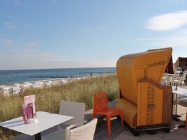 Um restaurante à beira-mar com mesas ao ar livre e vista para o mar, com uma placa que diz 'EIS'.