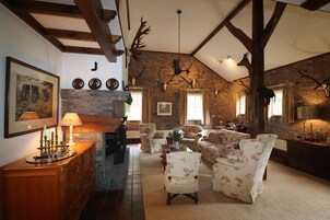 Uma sala de estar rústica com vigas de madeira aparentes, lareira e decorações de chifres de veado.