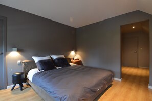 Quarto com cama, mesas de cabeceira e porta.