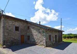 Um edifício de pedra com duas portas, uma janela e um caminho de entrada de cascalho.