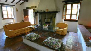 Uma sala de estar com lareira, dois sofás, uma mesa de centro e piso de tijolos.