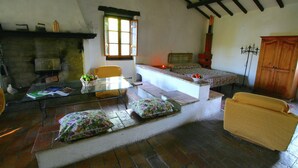 Um quarto rústico com lareira, uma cama, uma cadeira e um armário de madeira.