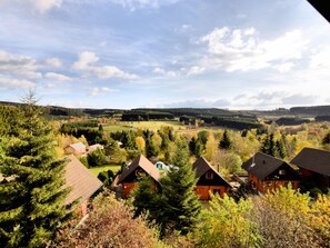Paisagem rural com casas rodeadas por árvores e campos abertos.