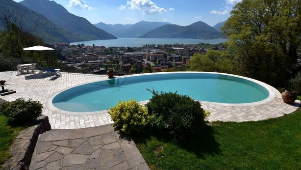 Piscina com vista para um lago e montanhas.