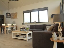 Uma sala de estar moderna com sofá, mesa de centro e área de jantar.