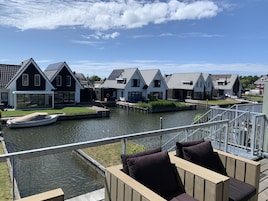 Vista para o rio com casas modernas, um cais e um deck de madeira com almofadas.