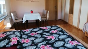 Um quarto com uma cama, uma mesa com cadeiras, uma parede com uma frase motivacional e uma porta de madeira.