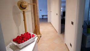 Um corredor com um banco branco, um cavalete de madeira com um chapéu e uma cesta de rosas vermelhas.