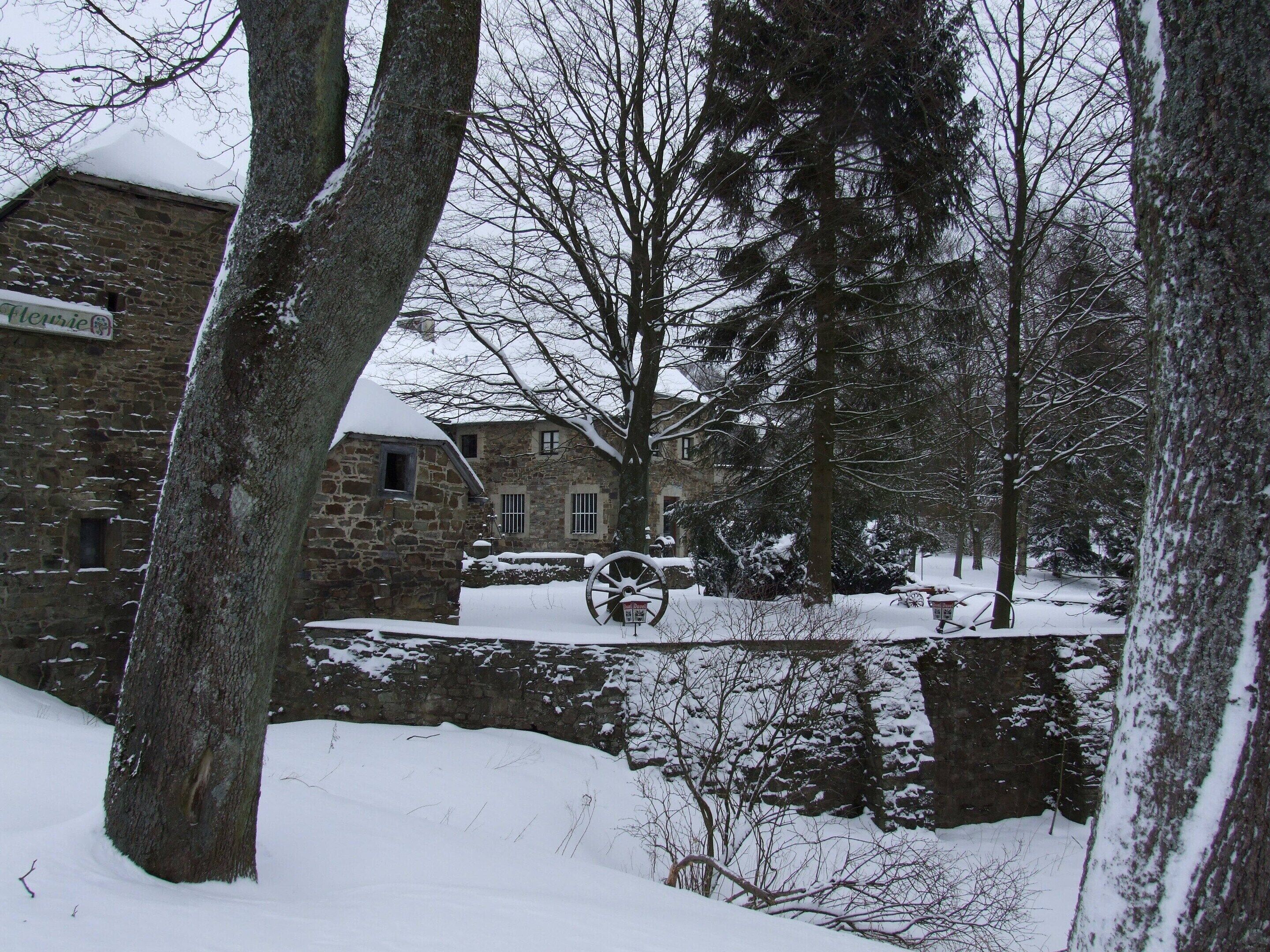 Um edifício de pedra com telhado coberto de neve e uma placa que diz 'Hotel'.