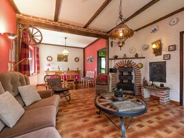 Uma sala de estar aconchegante com teto de madeira, lareira e área de jantar com mesa e cadeiras.