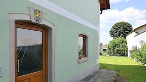Um edifício com fachada verde, porta de madeira e uma pequena janela.
