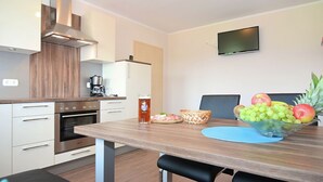 Uma cozinha moderna com forno embutido, cafeteira e TV fixada na parede.