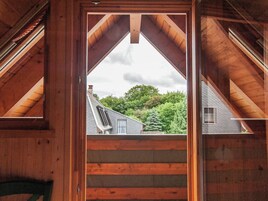 Interior em madeira com vista para uma casa pela janela.